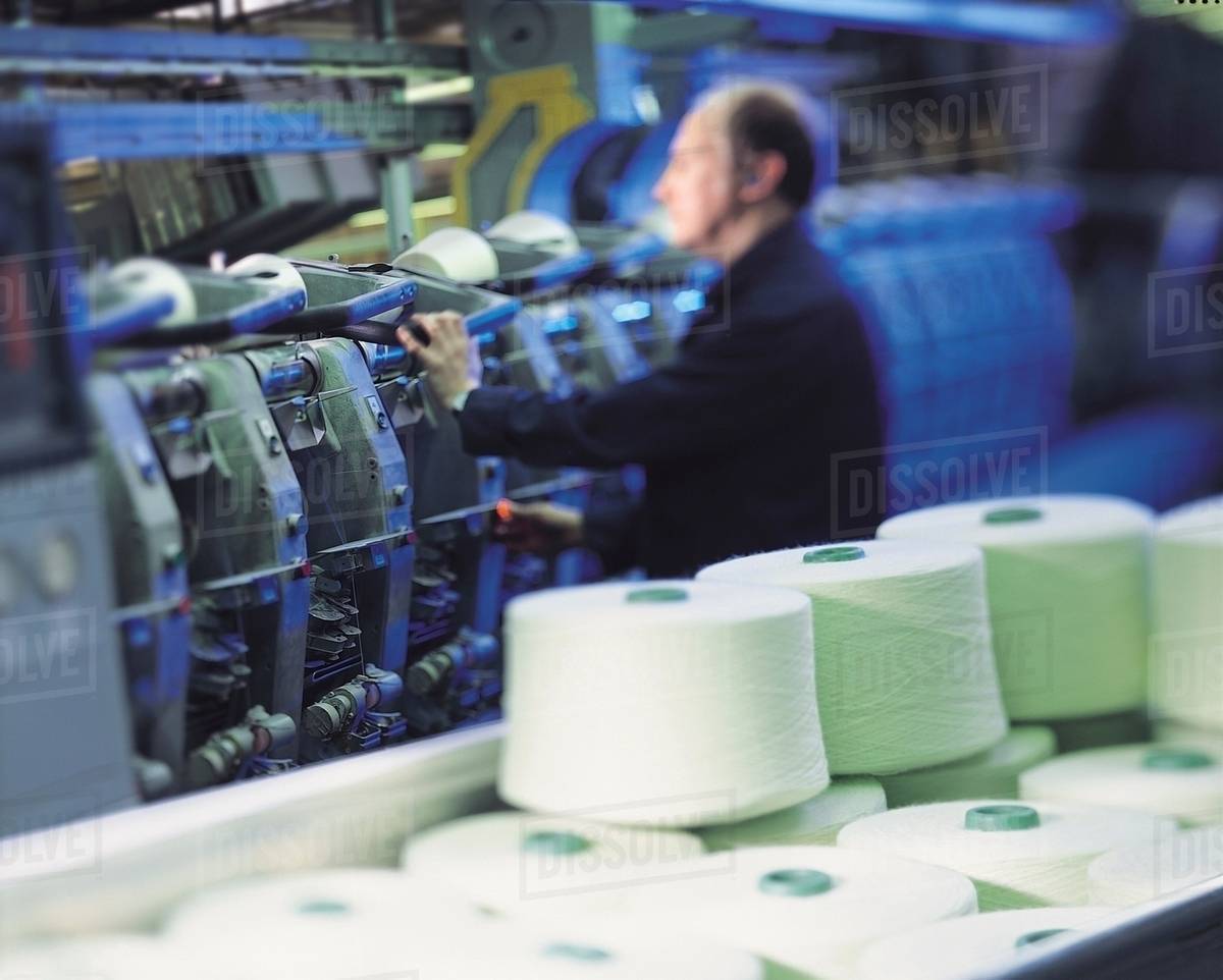 Worker at weaving machine in factory - Stock Photo - Dissolve