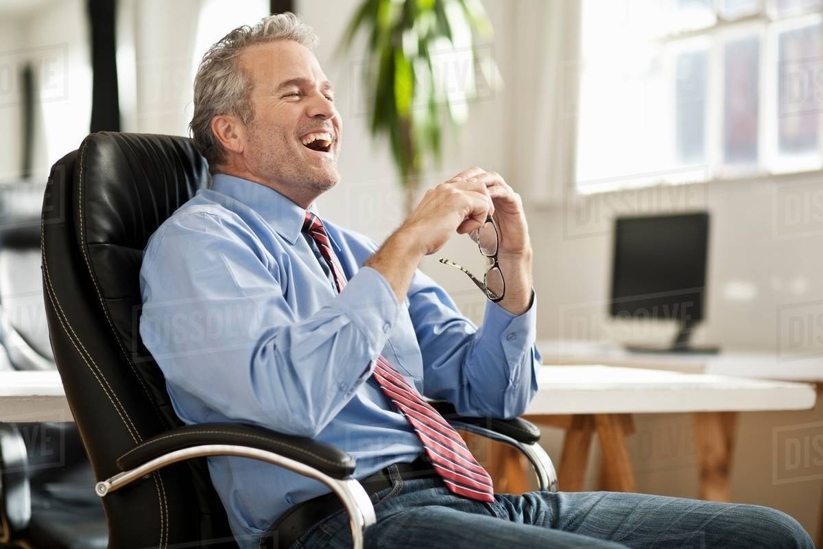 Businessman laughing at desk - Stock Photo - Dissolve