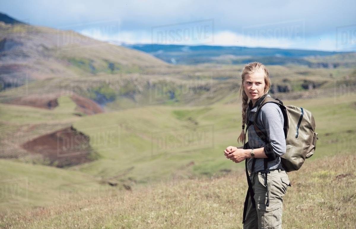 Hiker wearing backpack on hillside - Royalty-free Stock Photo | Dissolve