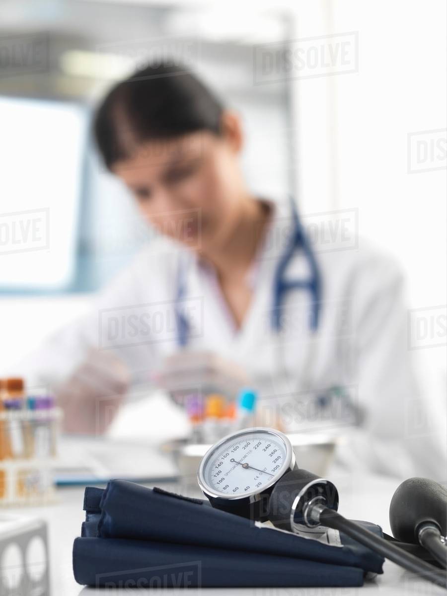 Female doctor examining test tube at desk in clinic - Royalty-free ...