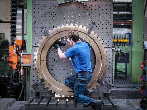 Engineer fitting gear wheel on lathe in engineering factory - Stock ...