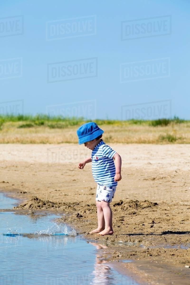 Small boy on beach throwing sand into sea, Marennes, Charente-Maritime ...