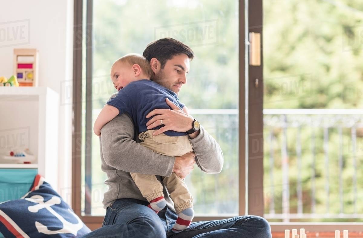Father hugging young son, indoors - Stock Photo - Dissolve