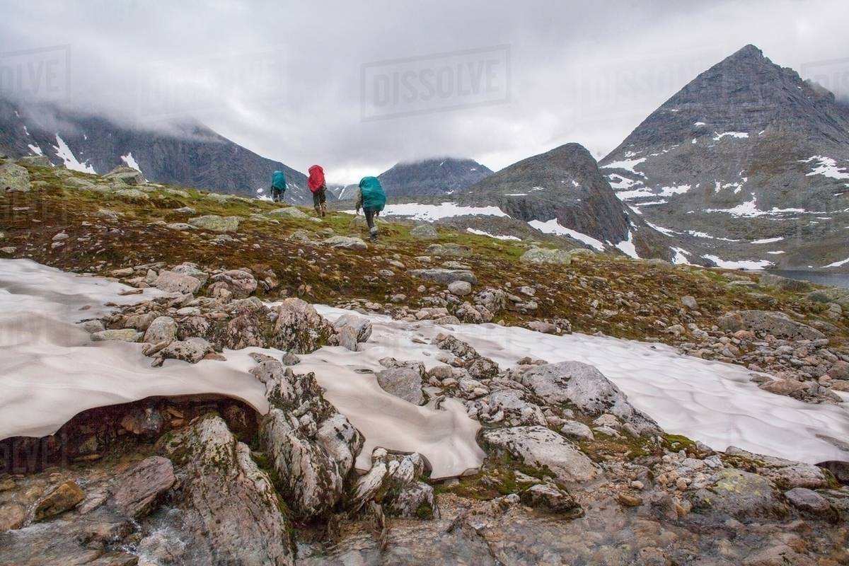 Rear view of three hikers hiking across frozen landscape, Ural ...