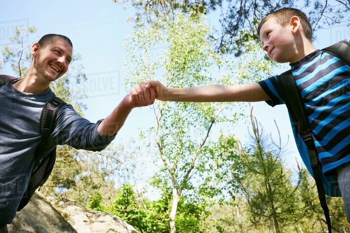 Male hiker giving son a helping hand in forest - Royalty-free Stock ...