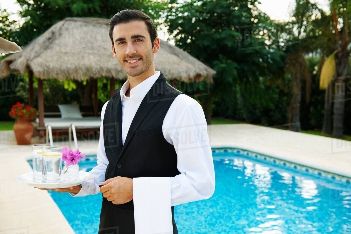 Hotel waiter holding tray by hotel pool - Royalty-free Stock Photo ...