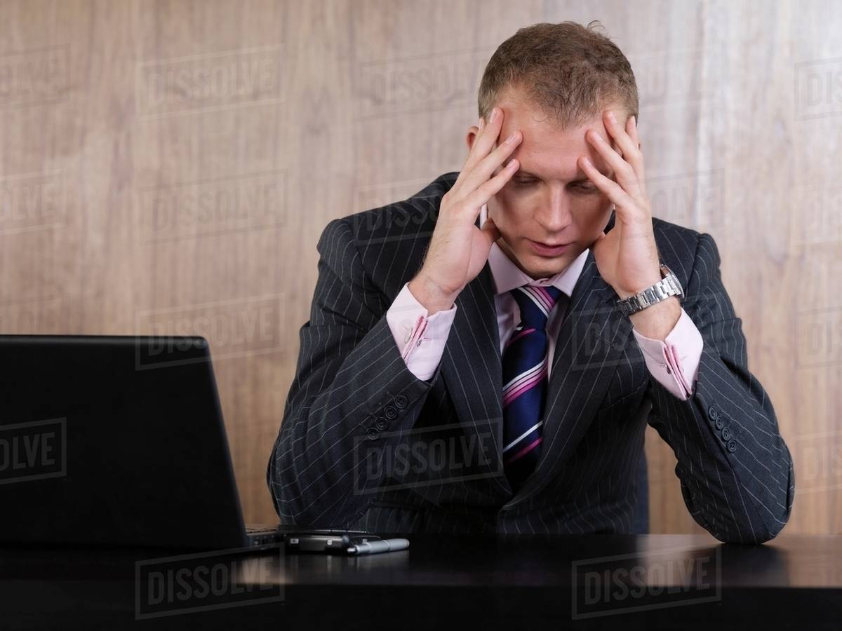 Business man head in hands in office - Stock Photo - Dissolve