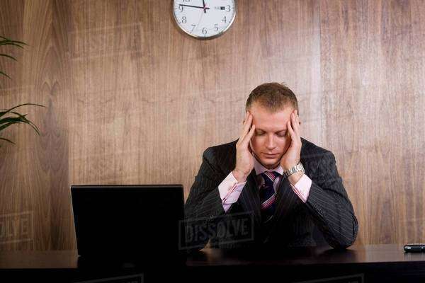 Business man head in hands at his desk - Stock Photo - Dissolve