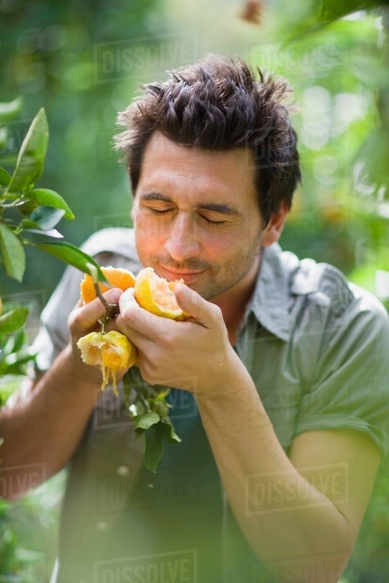 Man smelling at orange - Royalty-free Stock Photo | Dissolve