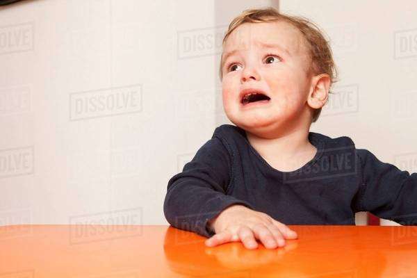 Little boy sitting on table crying - Royalty-free Stock Photo | Dissolve