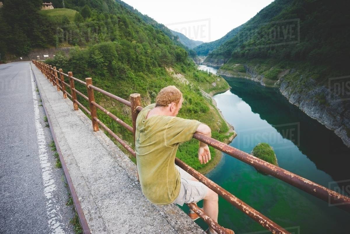 Man sitting on railings by road, Lake Garda, Italy - Royalty-free Stock ...