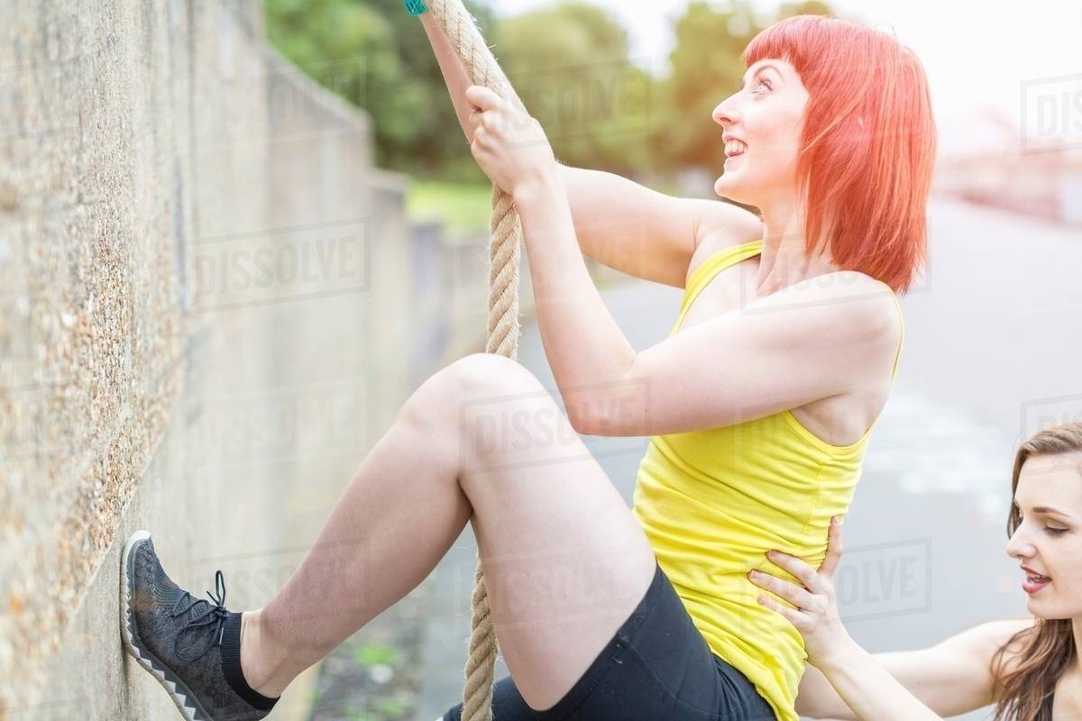 Young women climbing over wall with rope - Royalty-free Stock Photo ...