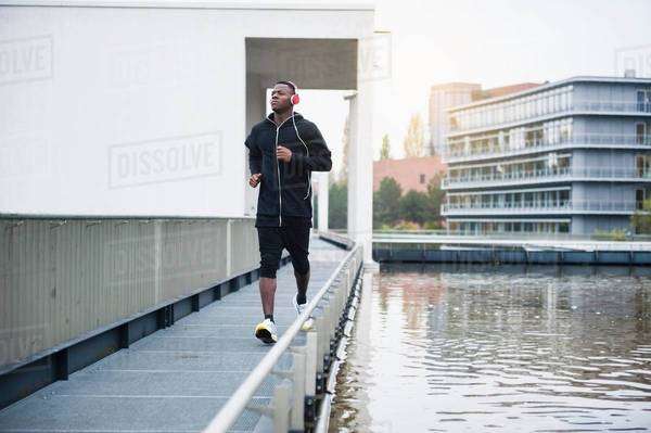 Young man running beside river - Stock Photo - Dissolve