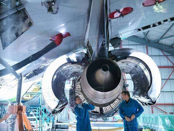 Engineers working on jet engine in aircraft maintenance factory - Stock ...