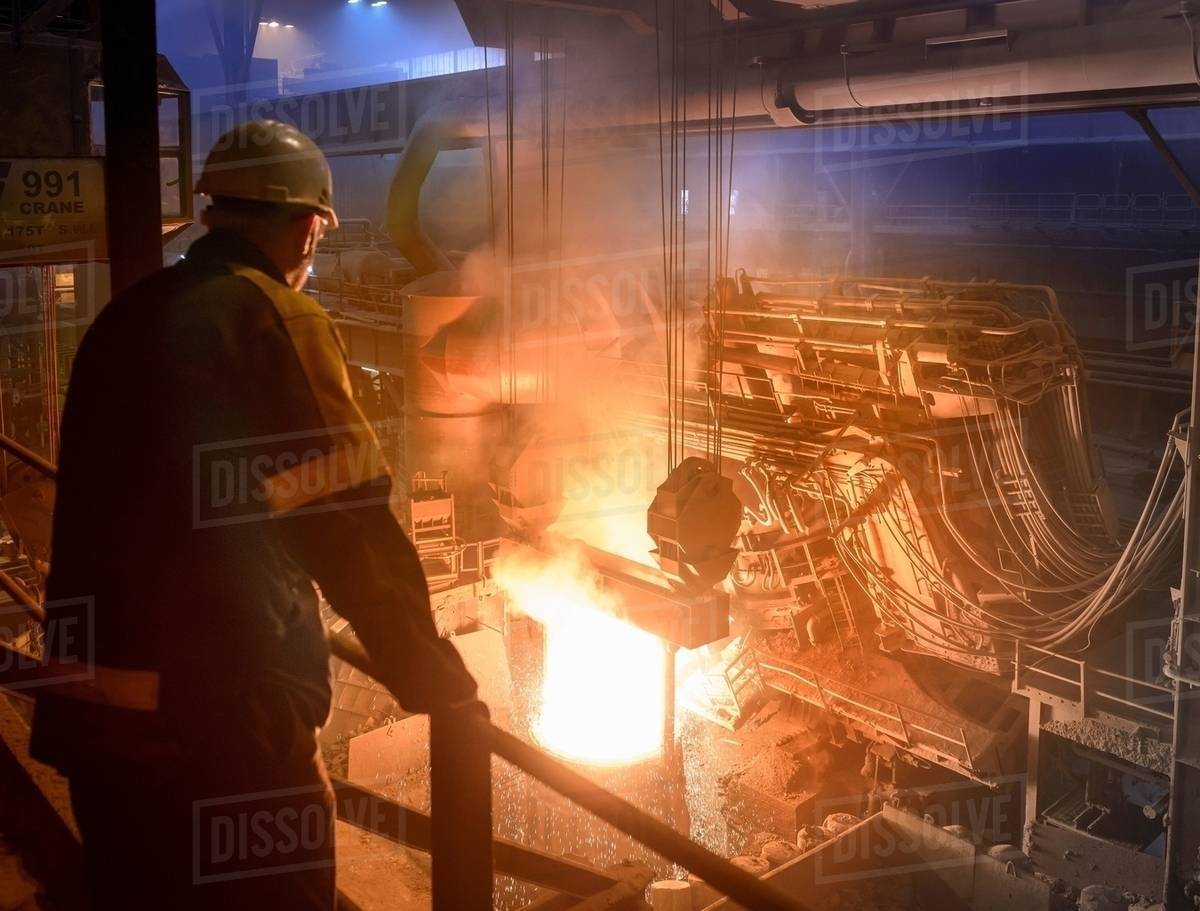 Steel worker inspecting pouring molten steel - Stock Photo - Dissolve