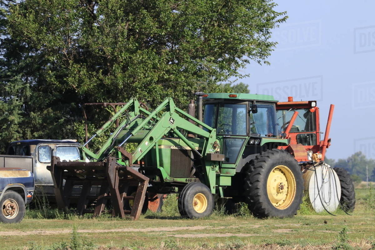 John Deere farm tractor with a loader on the front in a farm field with ...