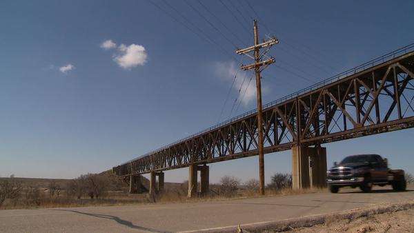 An iron railroad bridge in Western Kansas. A pick-up truck drives by ...