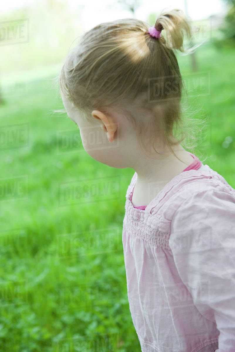 Toddler girl outdoors, looking over shoulder - Stock Photo - Dissolve