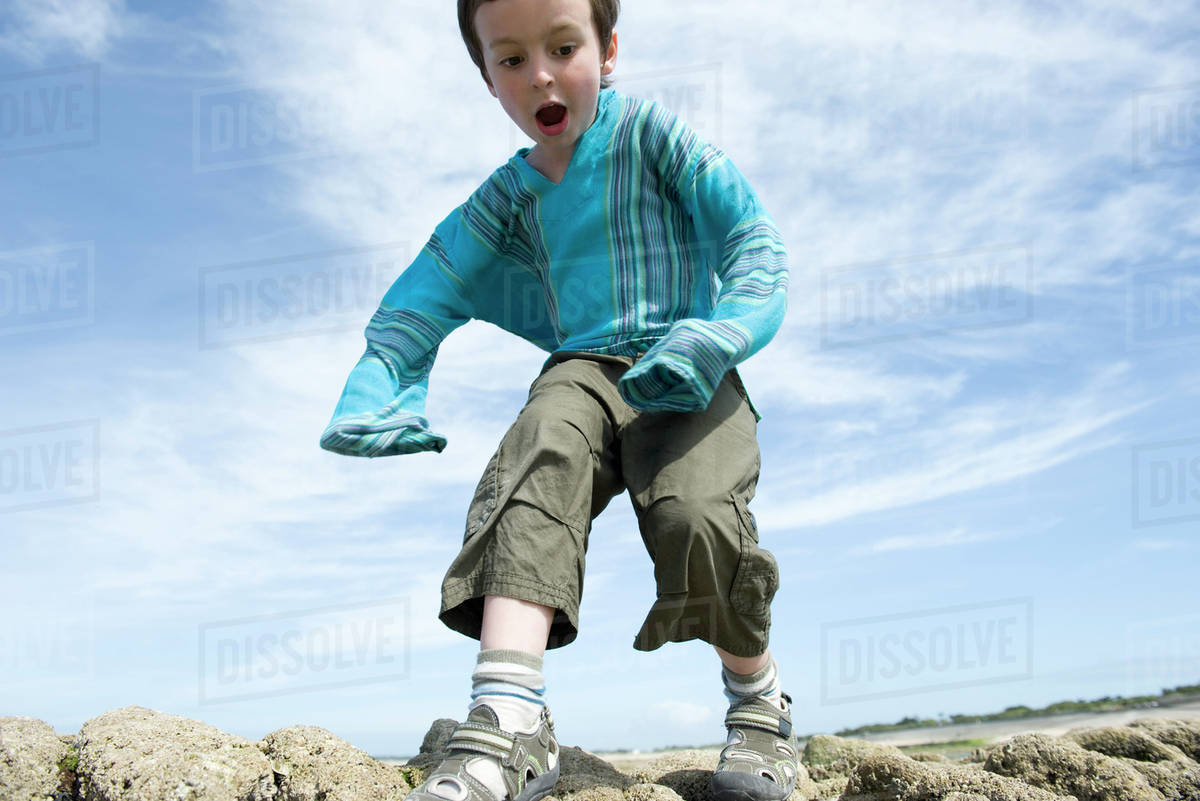 Boy playing outdoors, low angle view - Stock Photo - Dissolve