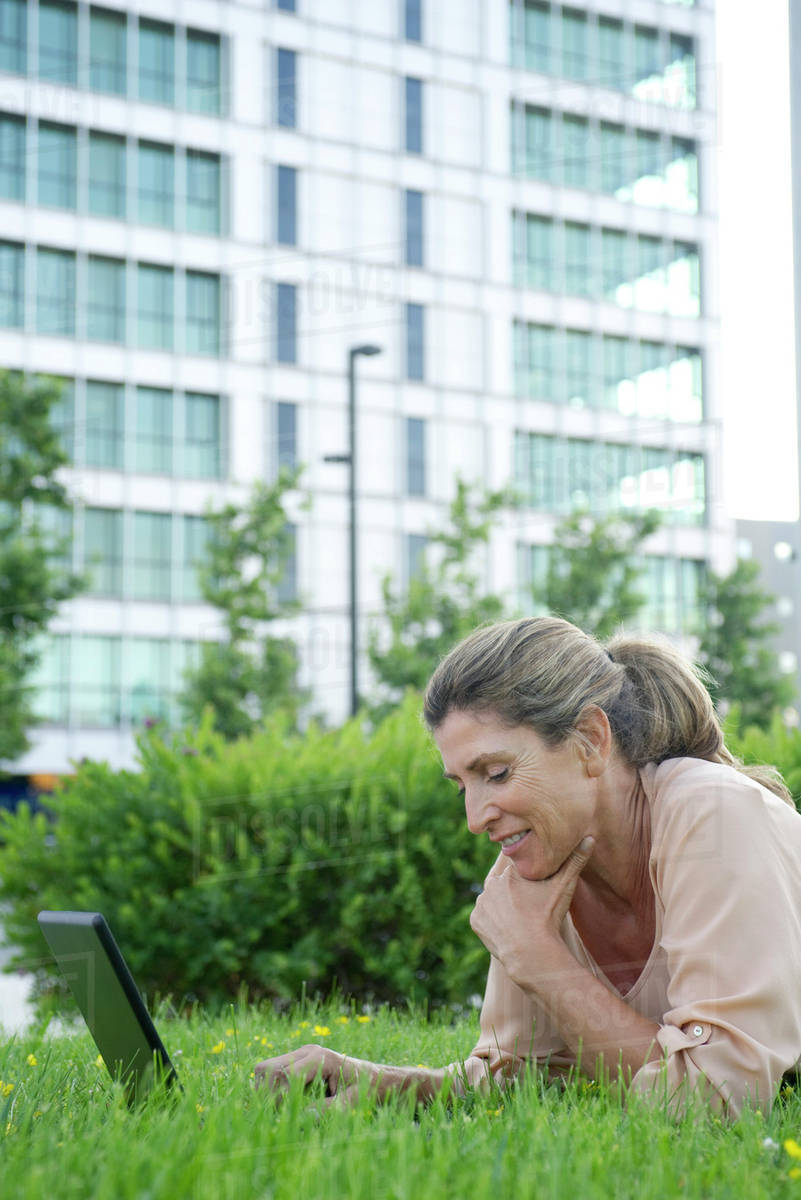 Woman lying in grass using laptop computer - Royalty-free Stock Photo ...