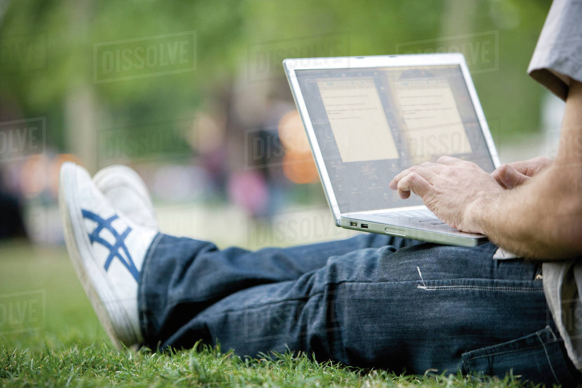 Man using laptop computer outdoors - Stock Photo - Dissolve