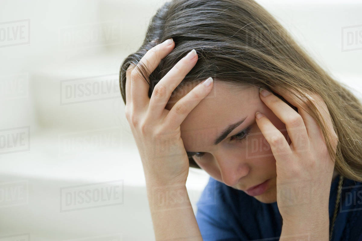 Young woman holding head and looking down - Royalty-free Stock Photo ...