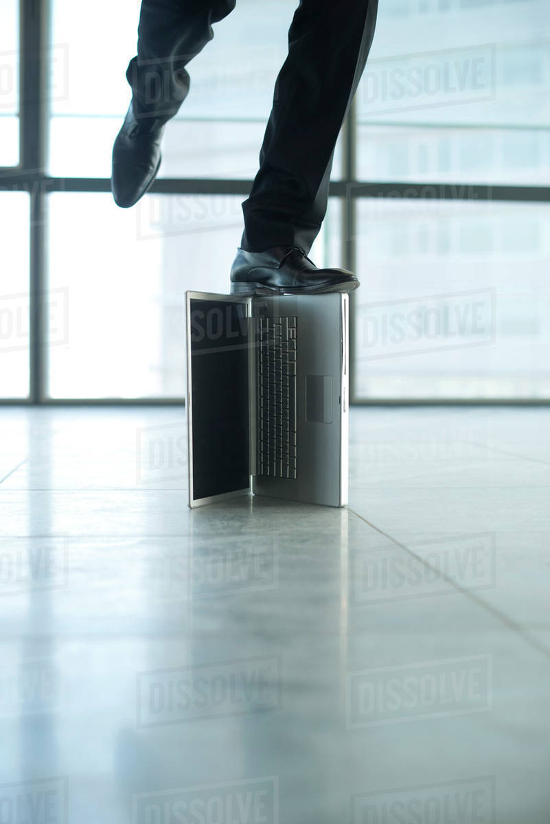 Man standing on top of laptop computer, low section - Stock Photo ...