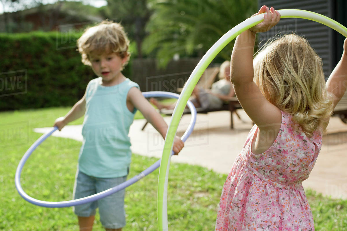Children playing with plastic hoops outdoors - Stock Photo - Dissolve