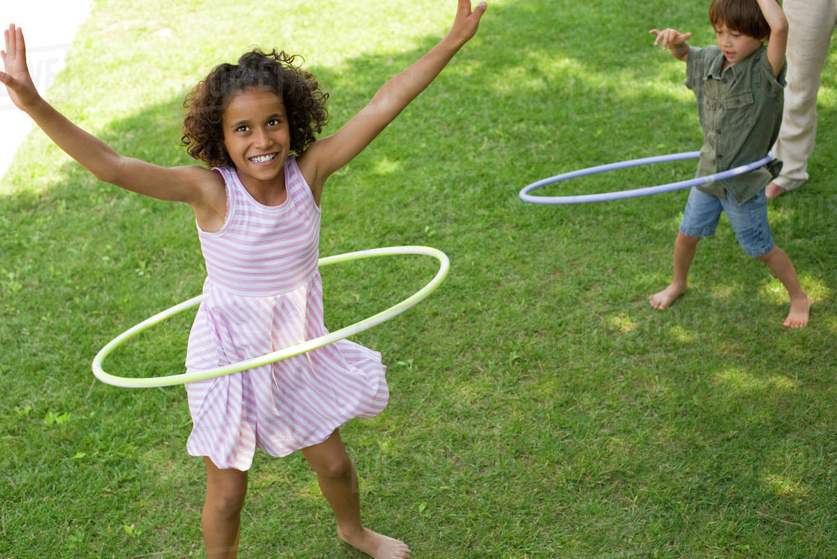 Children playing with plastic hoop outdoors - Stock Photo - Dissolve