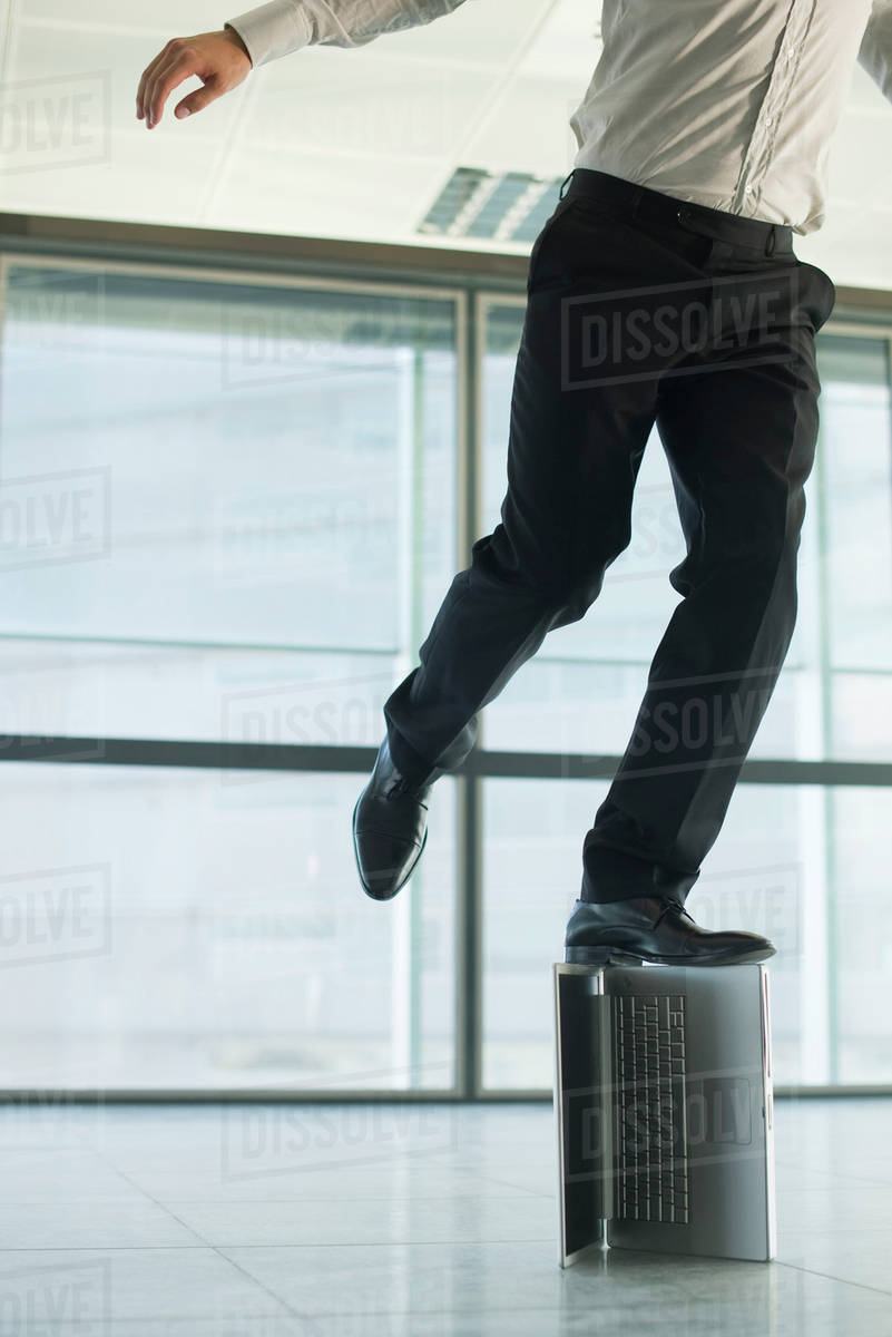 Man standing on top of laptop computer, low angle view - Royalty-free ...
