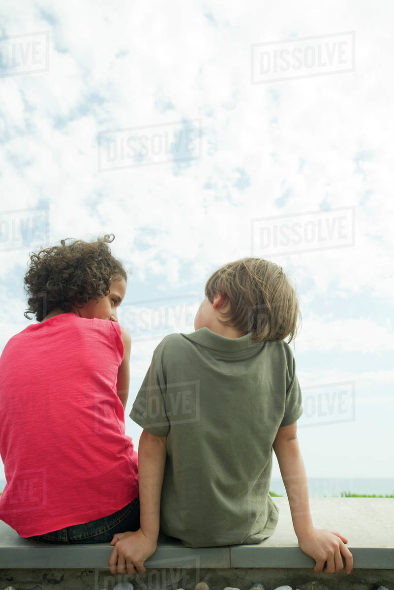 Girl and boy sitting side by side, rear view - Royalty-free Stock Photo ...
