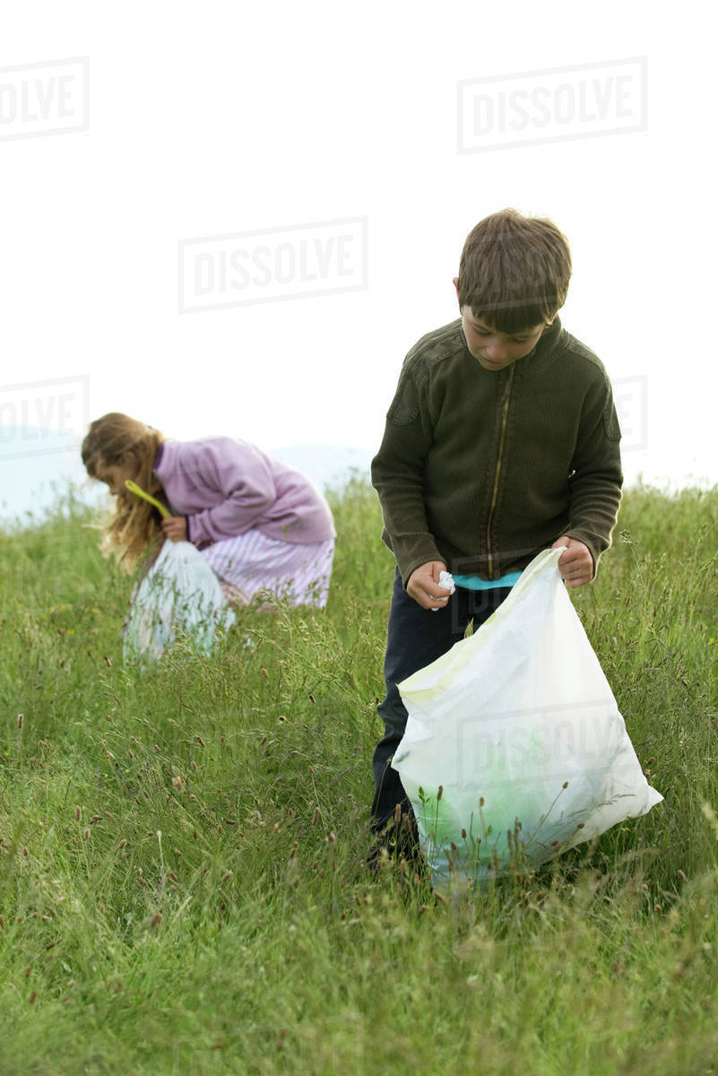 Children picking up trash in field - Royalty-free Stock Photo | Dissolve