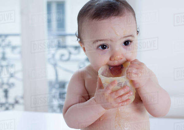 Infant biting plastic container covered in food, portrait - Stock Photo ...