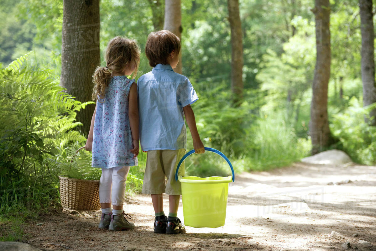 Children together on path in woods, girl carry basket and boy carrying ...