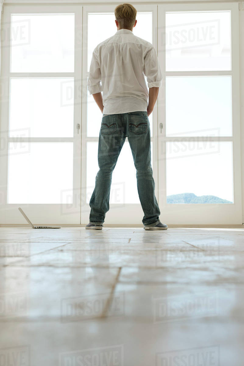 Man looking out window, rear view - Stock Photo - Dissolve