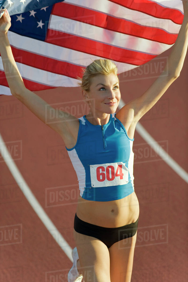 Woman running on track with American flag - Stock Photo - Dissolve