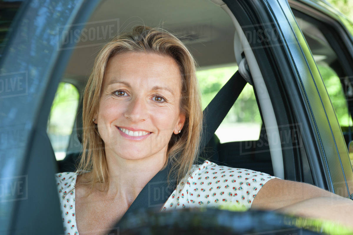 Woman in car, smiling out window, portrait - Stock Photo - Dissolve