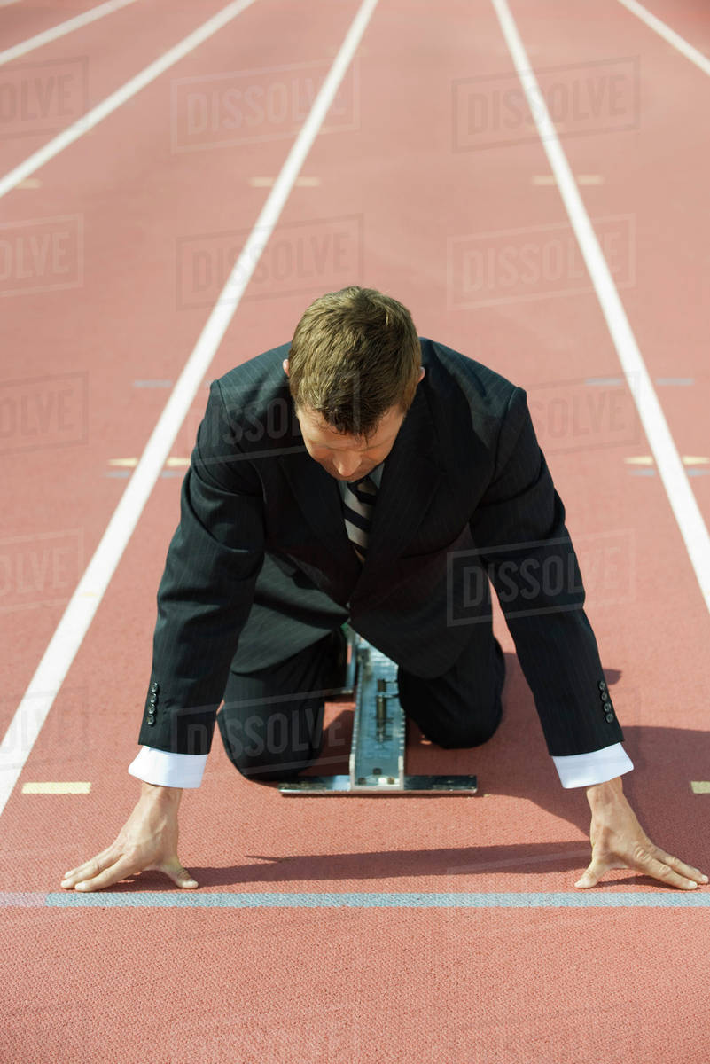 Businessman crouching at starting line on running track - Royalty-free ...