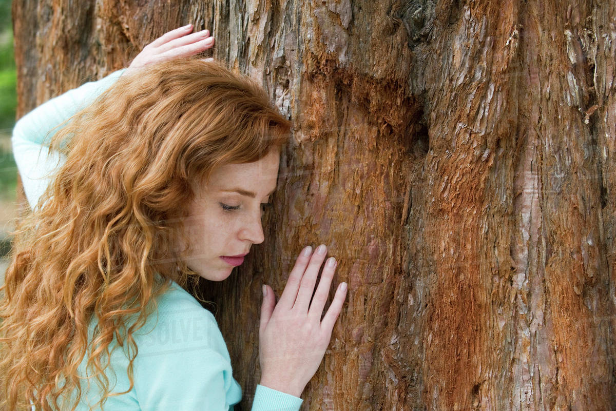 Young woman touching tree, portrait - Stock Photo - Dissolve
