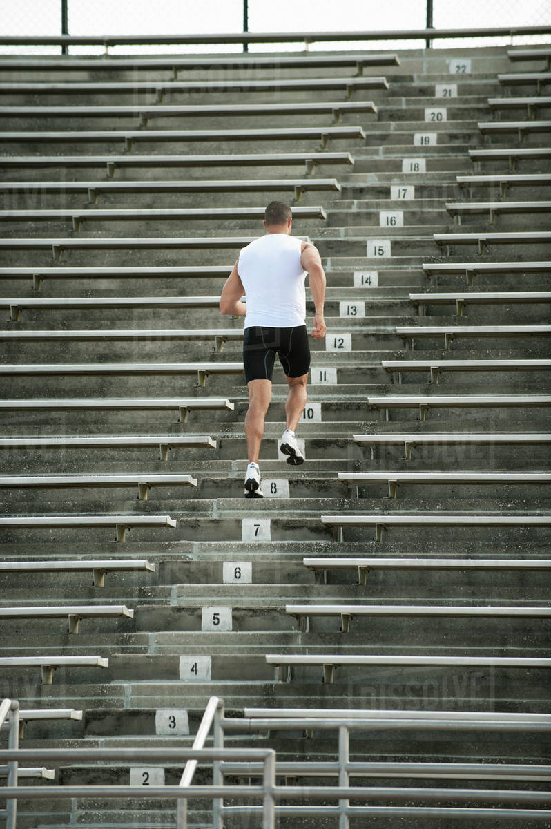 Man running up steps in stadium, rear view - Royalty-free Stock Photo ...
