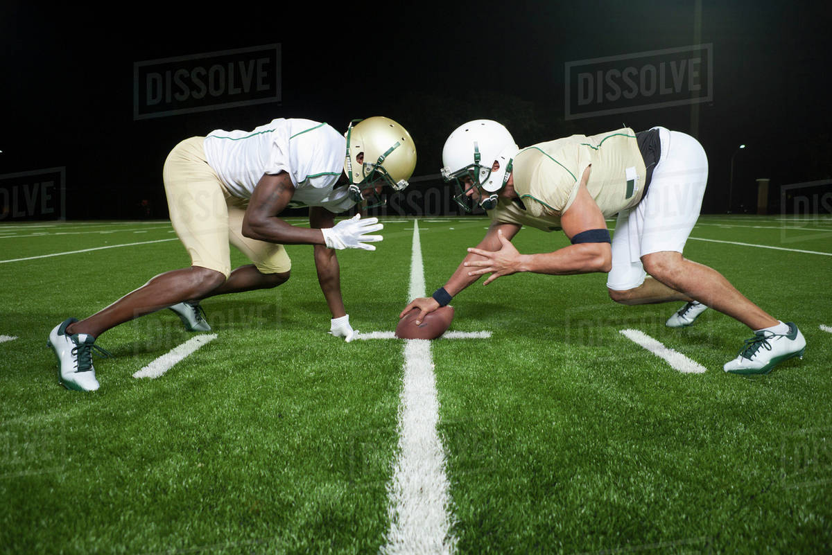 Opposing football players crouched at line of scrimmage - Royalty-free ...