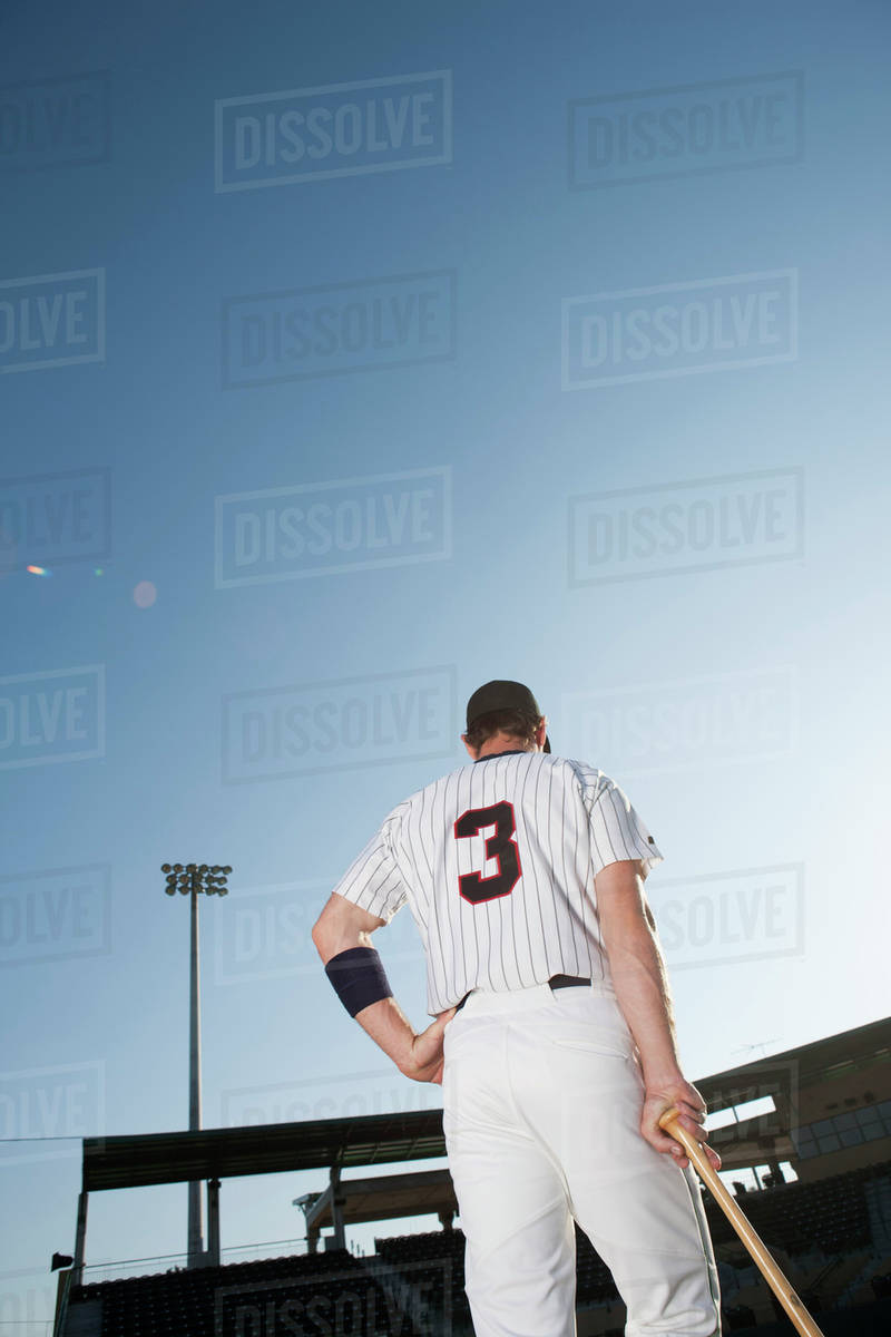 Baseball player standing with hand on hip, rear view - Stock Photo ...