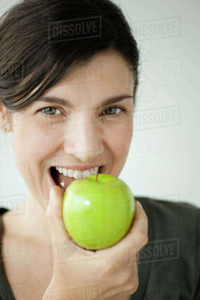 Mid-adult woman biting into apple - Royalty-free Stock Photo | Dissolve