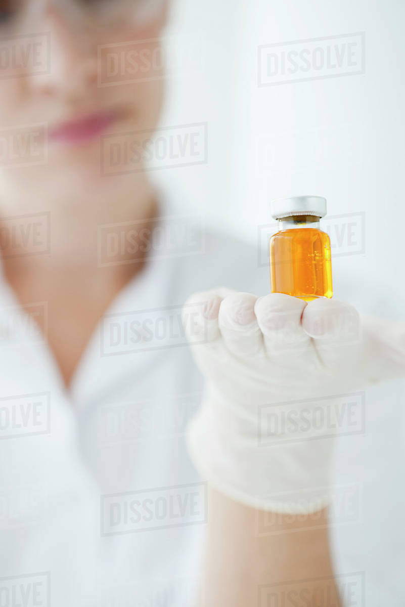 Scientist holding vial containing orange liquid - Royalty-free Stock ...