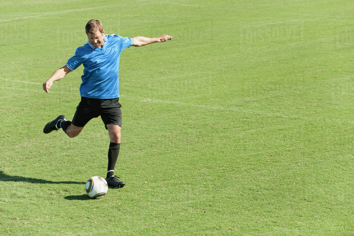 Soccer player kicking soccer ball on soccer field - Royalty-free Stock ...