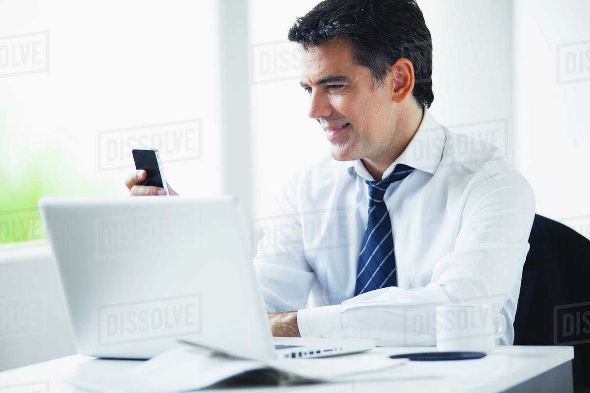 Businessman using cell phone at work - Stock Photo - Dissolve