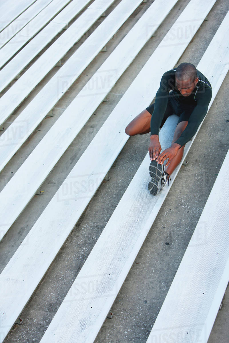 Man stretching on bleacher, high angle view - Stock Photo - Dissolve