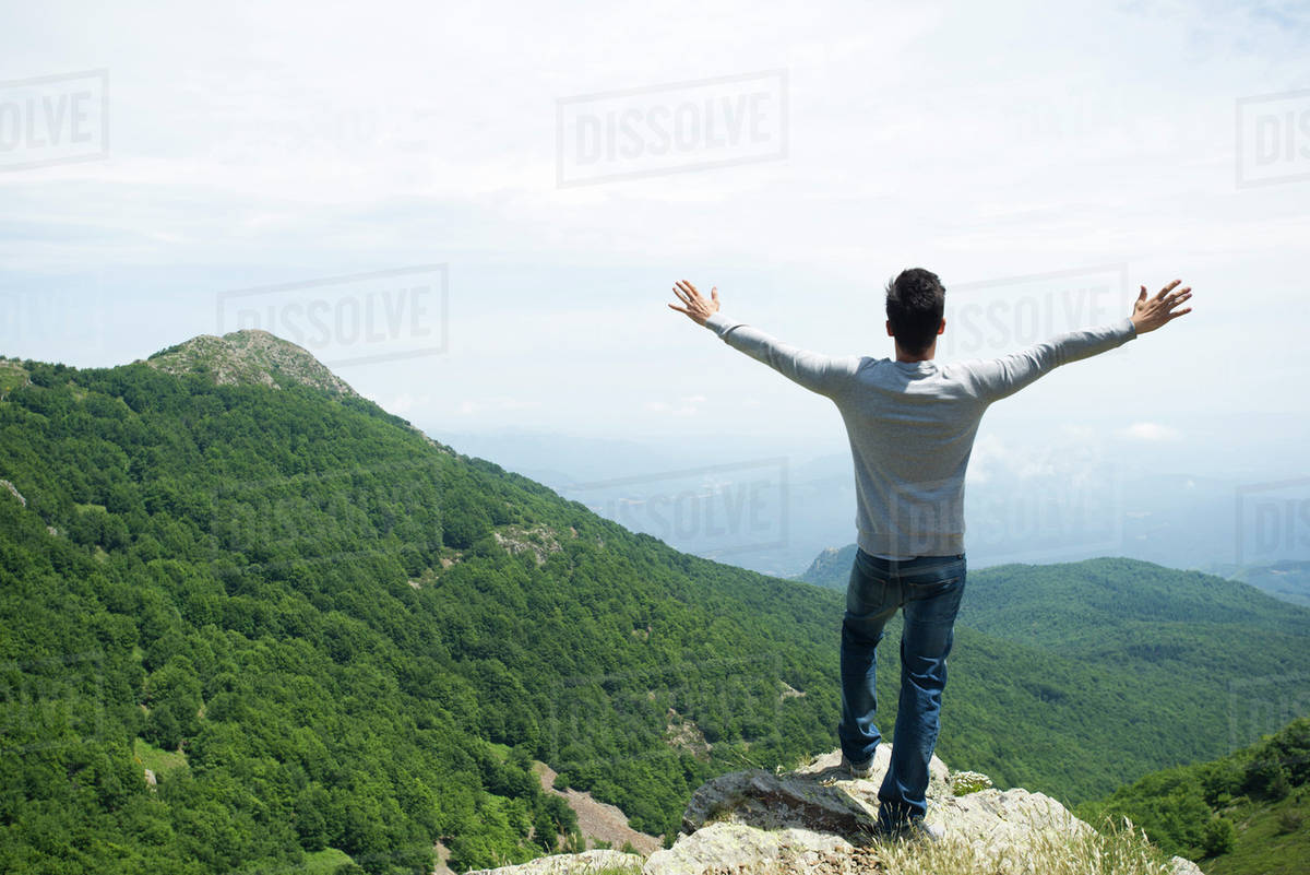 Man standing on rock looking at mountainscape - Stock Photo - Dissolve