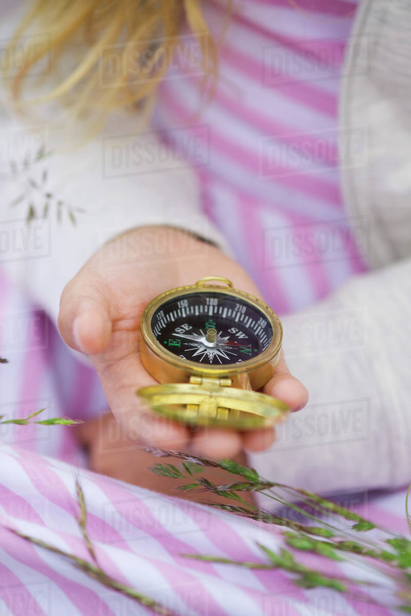 Girl holding compass, cropped - Stock Photo - Dissolve