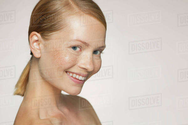 Young woman smiling coyly - Stock Photo - Dissolve